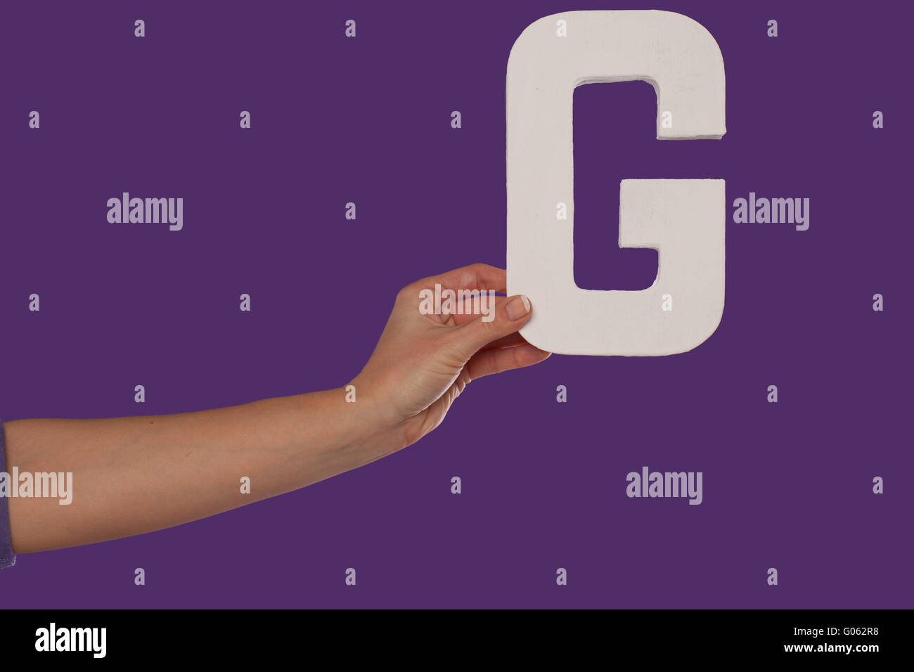 Female hand holding up the letter G from the left Stock Photo - Alamy