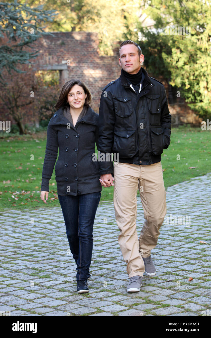 Young couple approaching walking hand in hand Stock Photo - Alamy