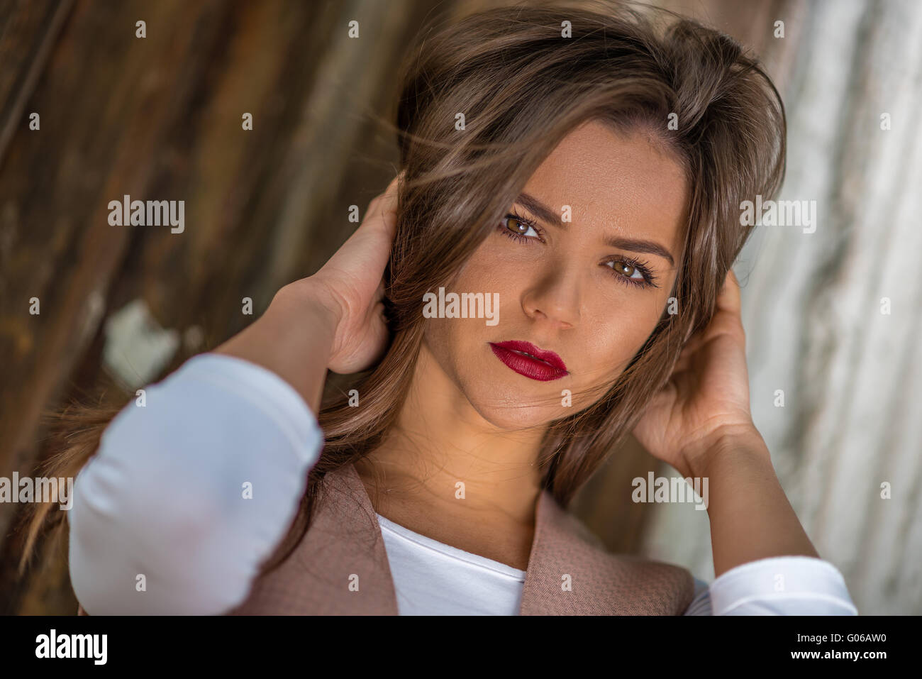Young woman with red lips and brown hair is posing against the rustic ...