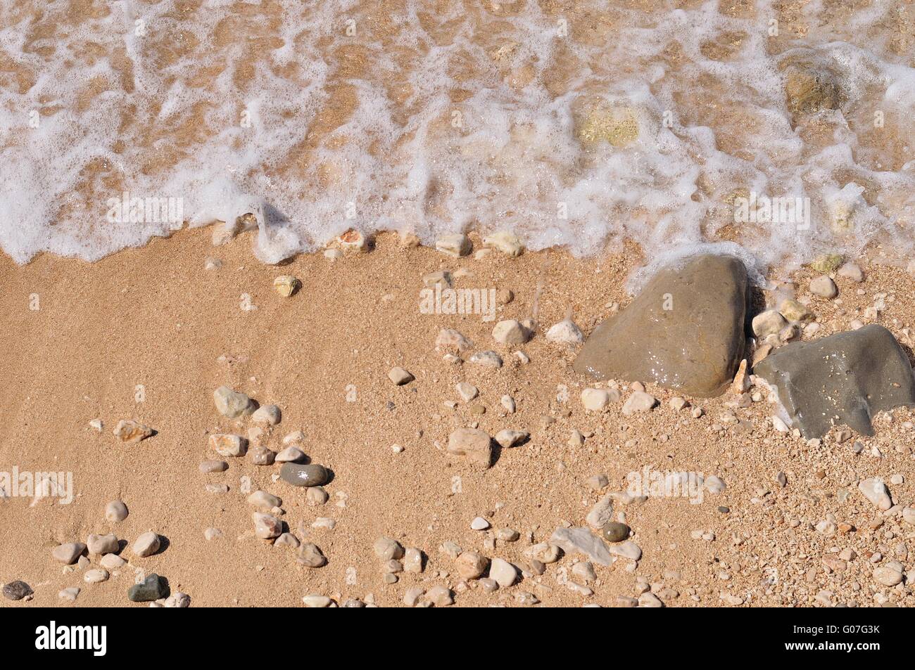 Sandy beach with pebbles and wave as natural background Stock Photo - Alamy