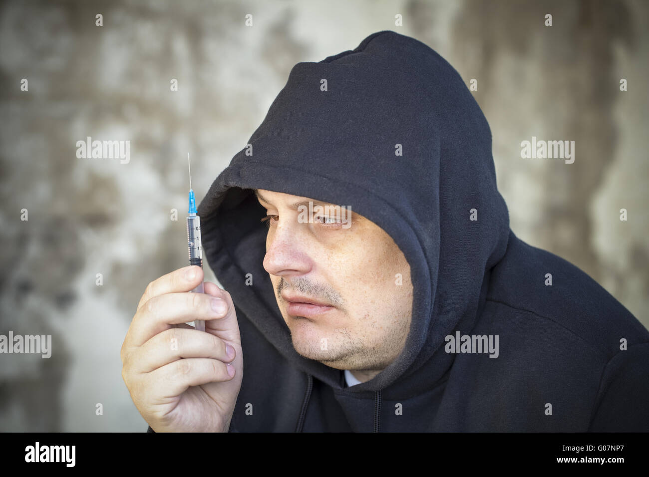 Drug addict men looks at the syringe in the hands Stock Photo - Alamy