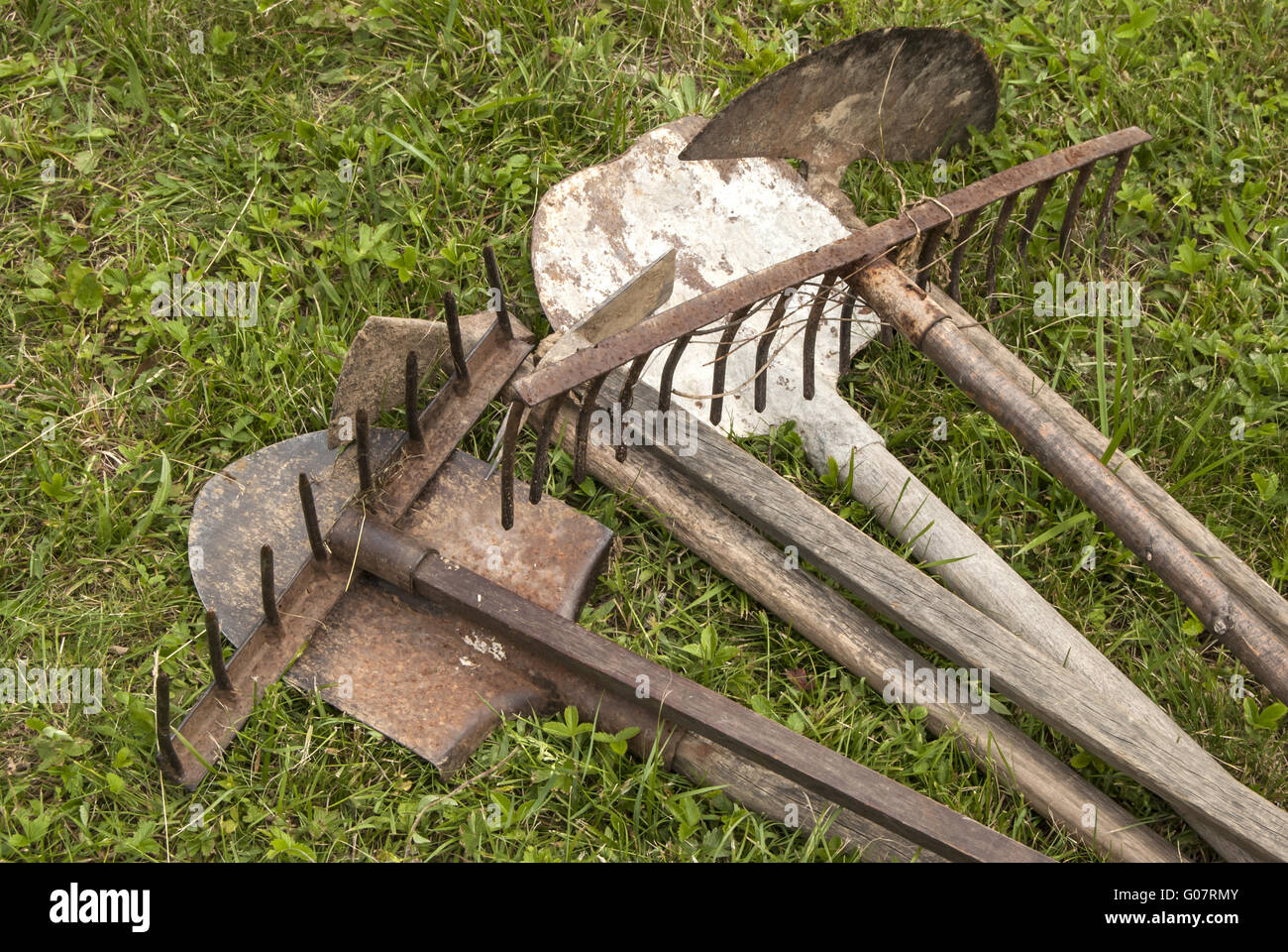 Used farm hand implements on green grass backgroun Stock Photo - Alamy