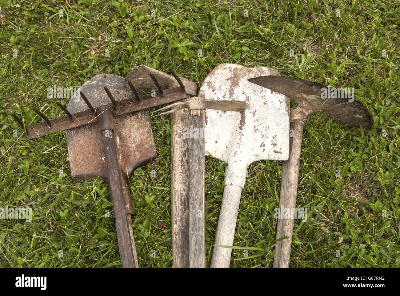Used farm hand implements on green grass backgroun Stock Photo - Alamy