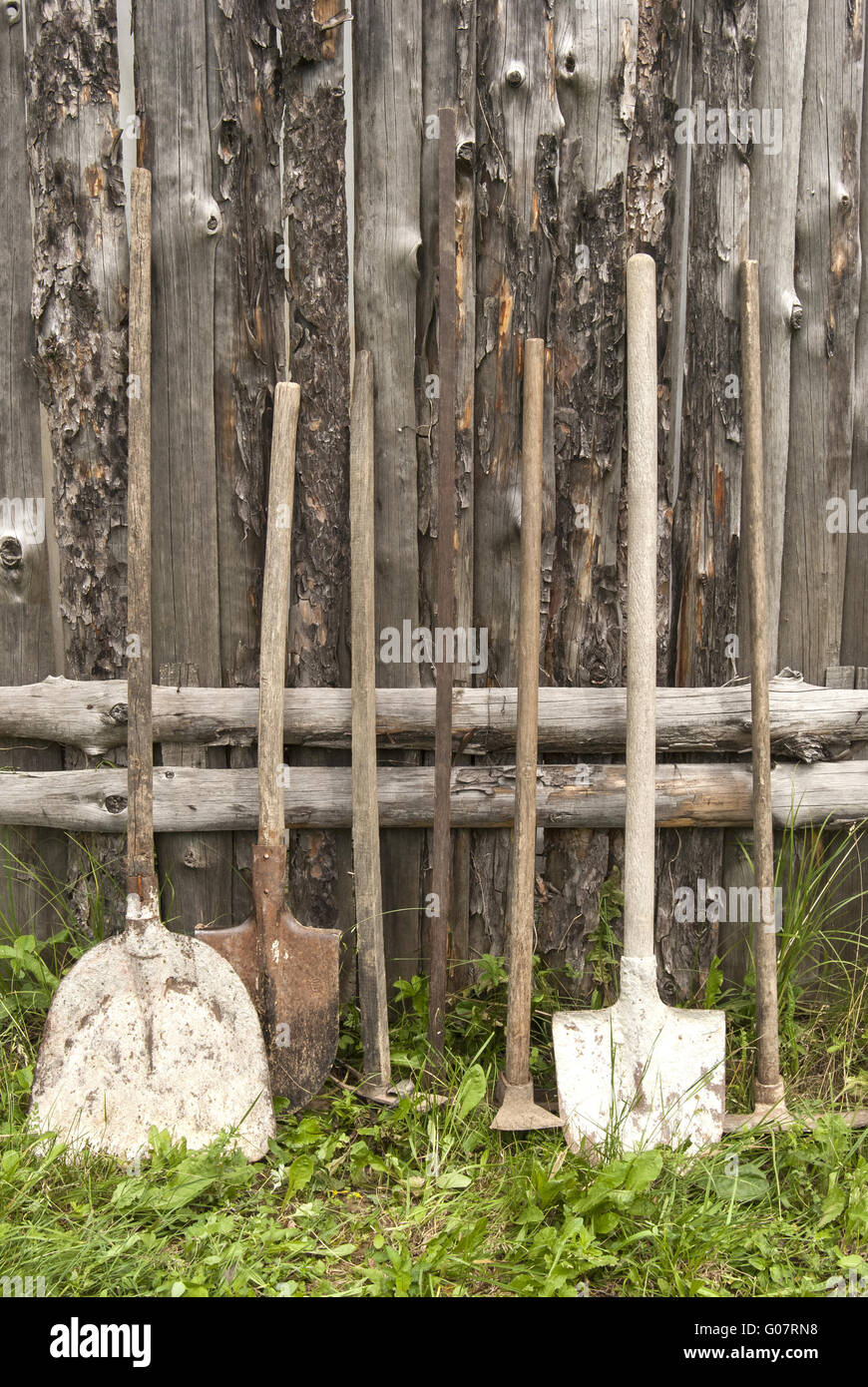 Used farm hand implements on wooden shed wall back Stock Photo - Alamy