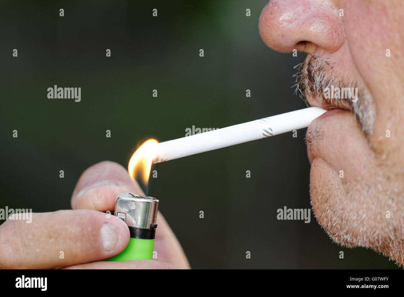 Smoking a cigarette against a dark background Stock Photo - Alamy