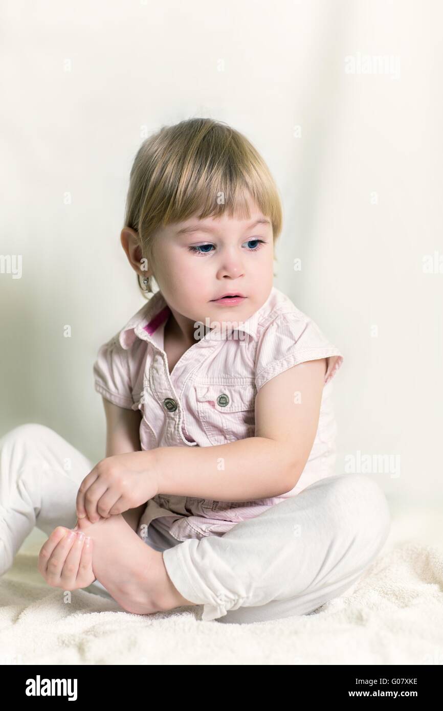 Portrait of a little girl how to hold the leg Stock Photo - Alamy