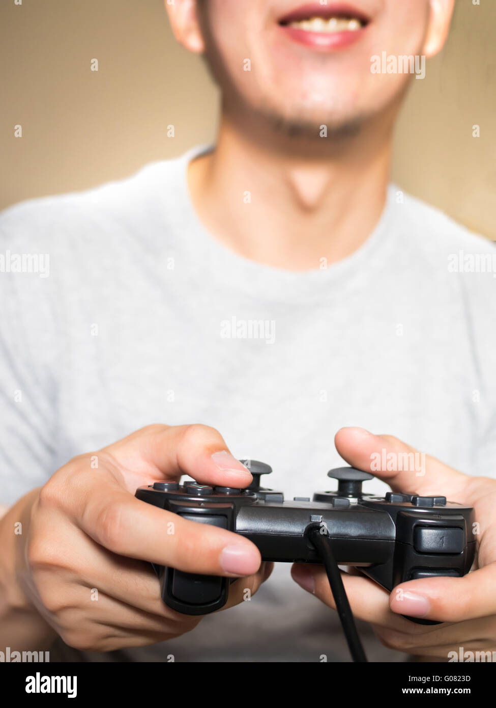 A young man holding game controller playing video games Stock Photo - Alamy