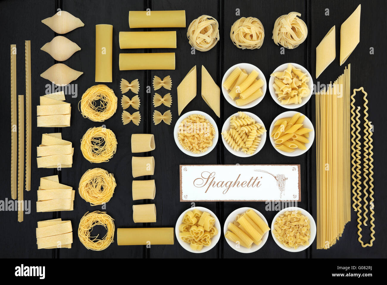 Large italian dried pasta selection with spaghetti sign over dark wood ...