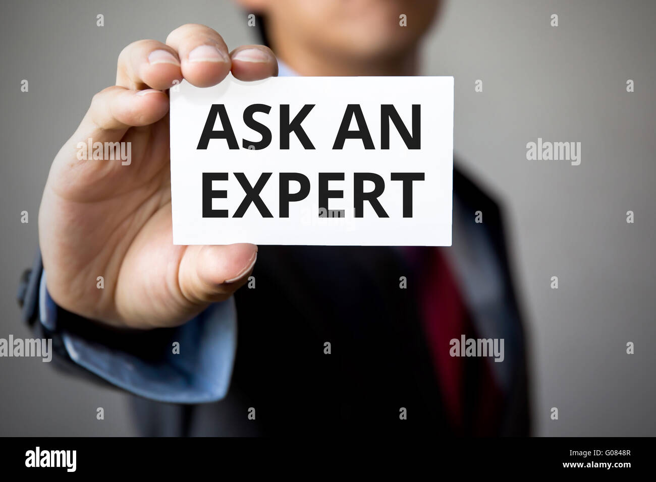 Businessman presenting 'Ask An Expert' word on white card Stock Photo ...