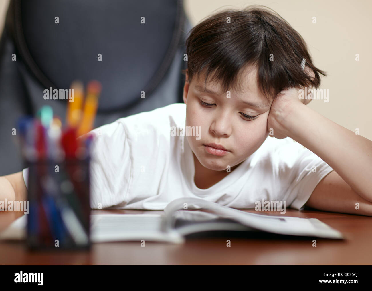 School boy studies hard over his book at home Stock Photo - Alamy
