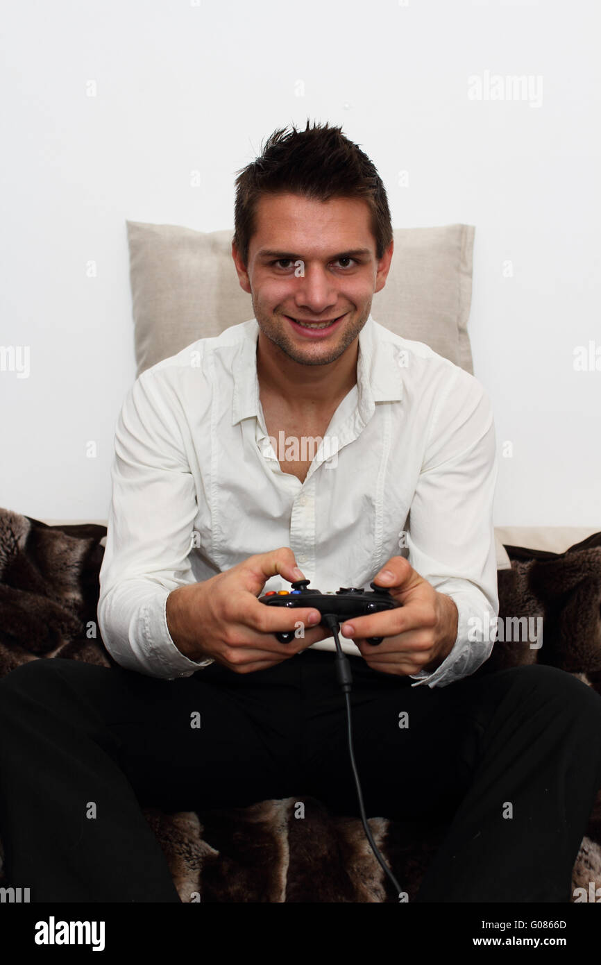 Smiling Gamer sitting on couch with controller and playing Stock Photo ...