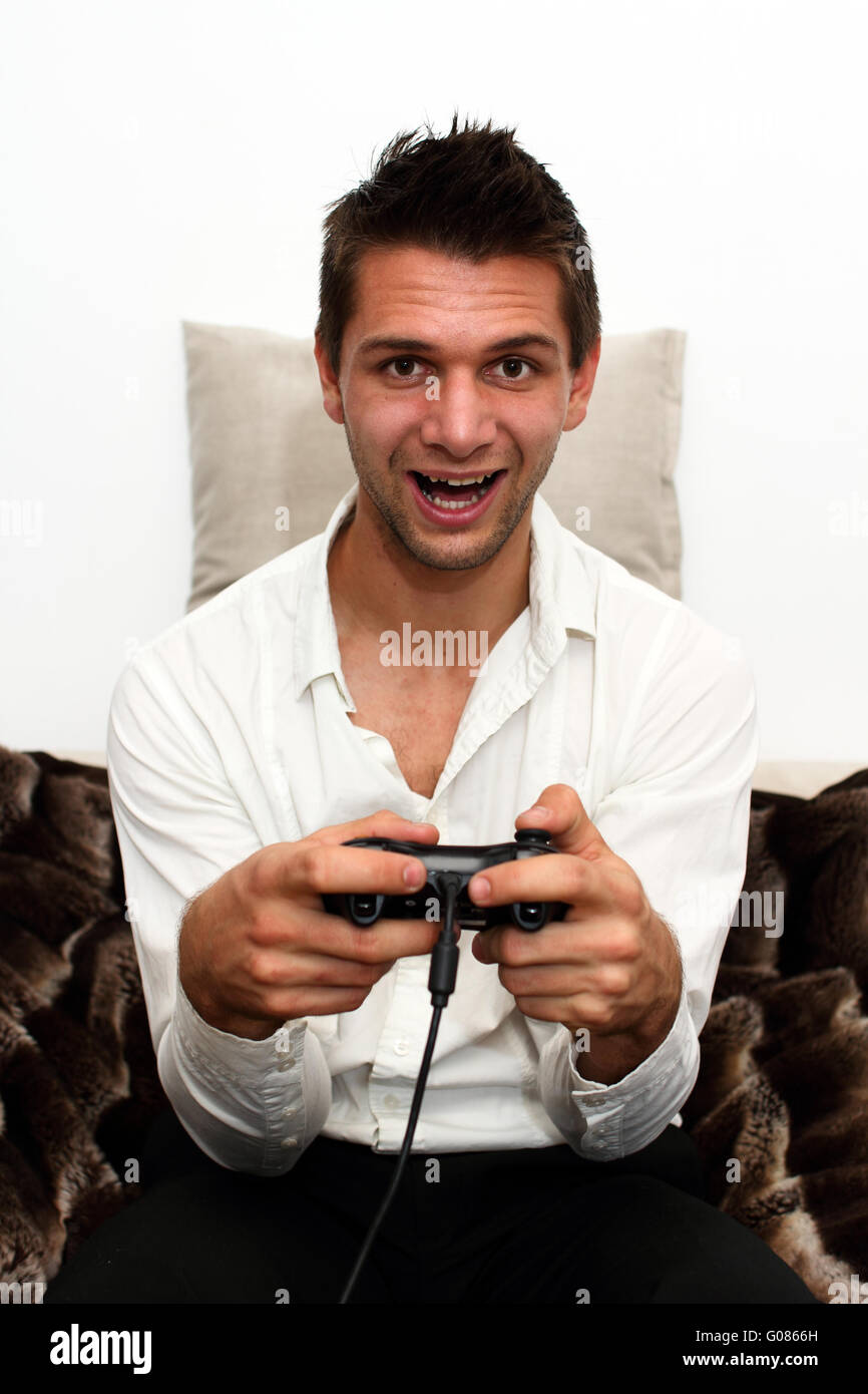 Smiling Gamer sitting on couch with controller and playing Stock Photo ...