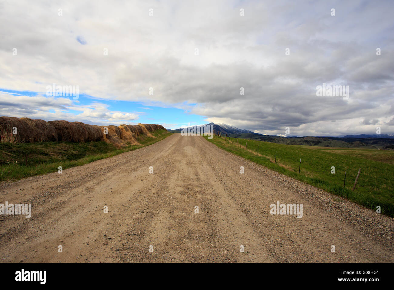 Dirt road with farmland and Rocky Mountains in background Stock Photo ...