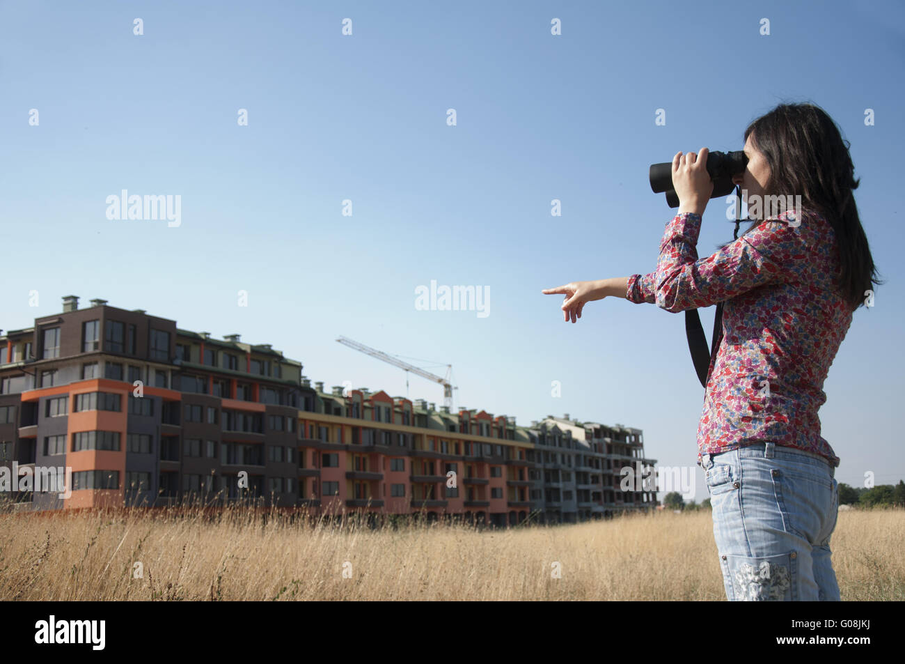 Woman watching with binoculars building construction Stock Photo - Alamy