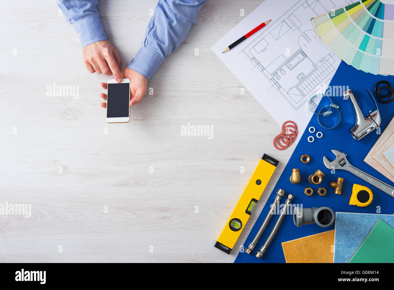 Male hands using a mobile phone next to plumbing work tools, tiles and ...