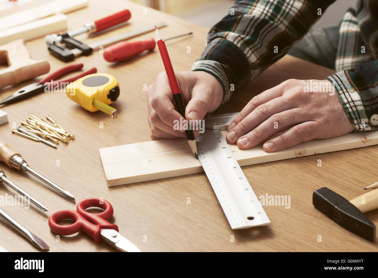 Man working on a DIY project and measuring a wooden plank with work ...