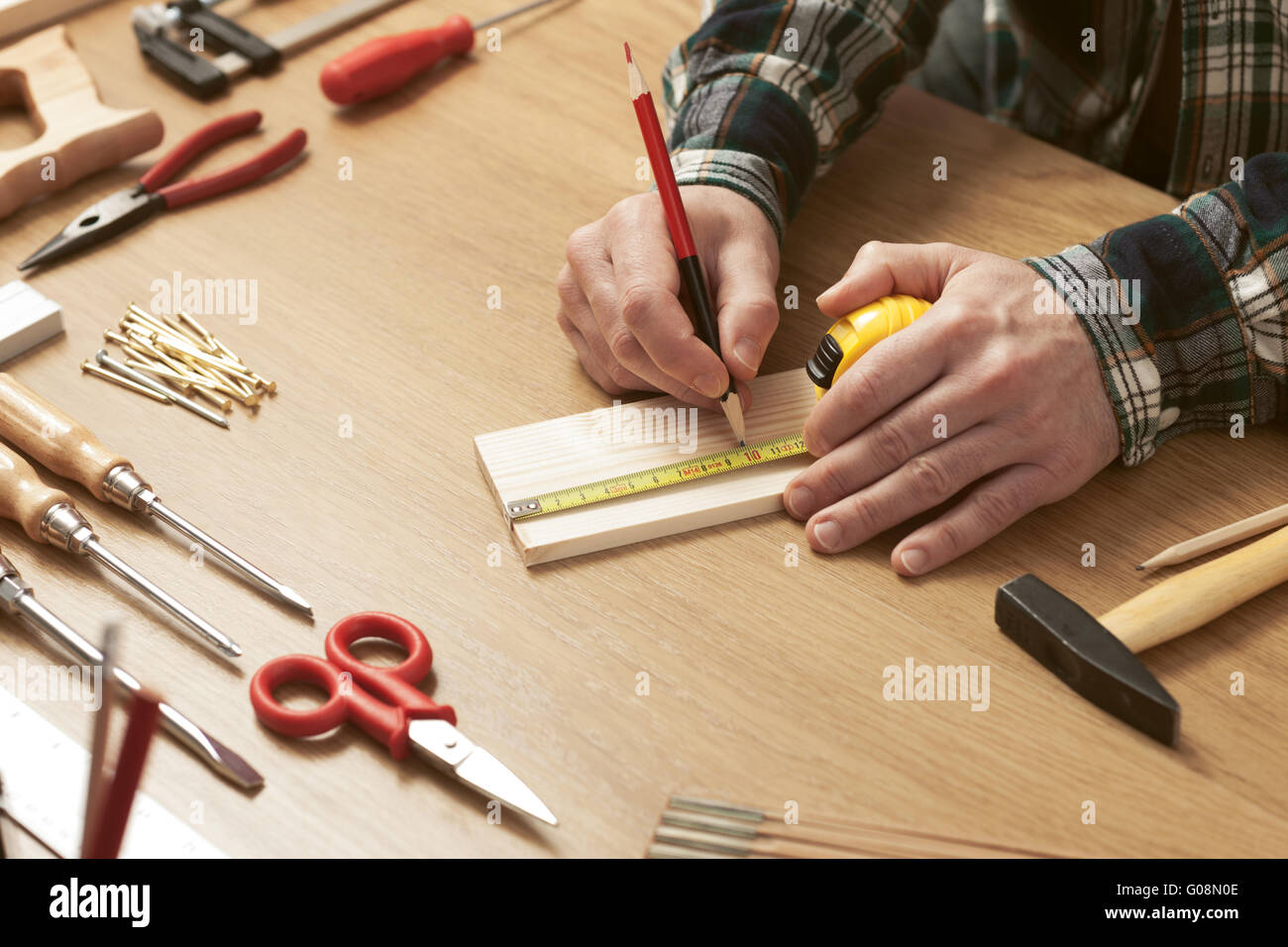 Man working on a DIY project and measuring a wooden plank with work ...