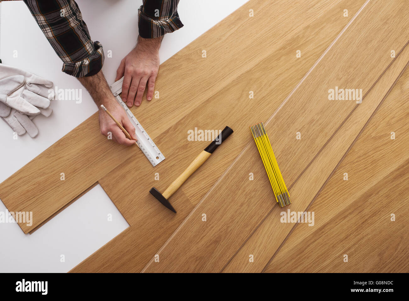 Carpenter installing a wooden flooring and measuring with a precision ...