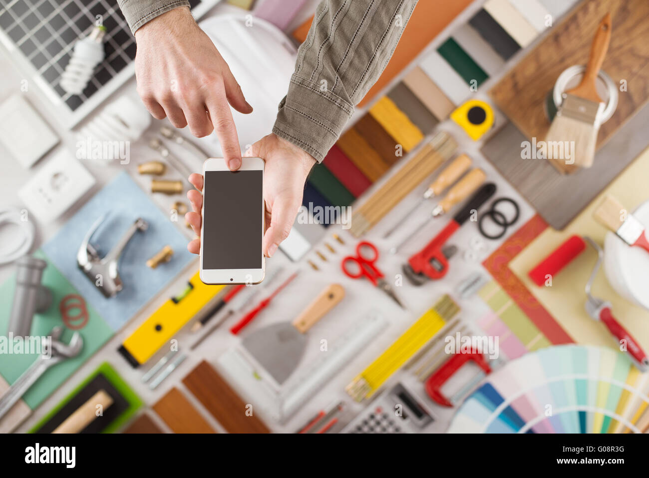 Male hands using a touch screen smart phone, build and home renovation ...