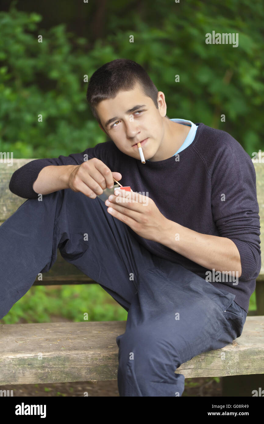 Boy with a cigarette on a bench in the park Stock Photo - Alamy