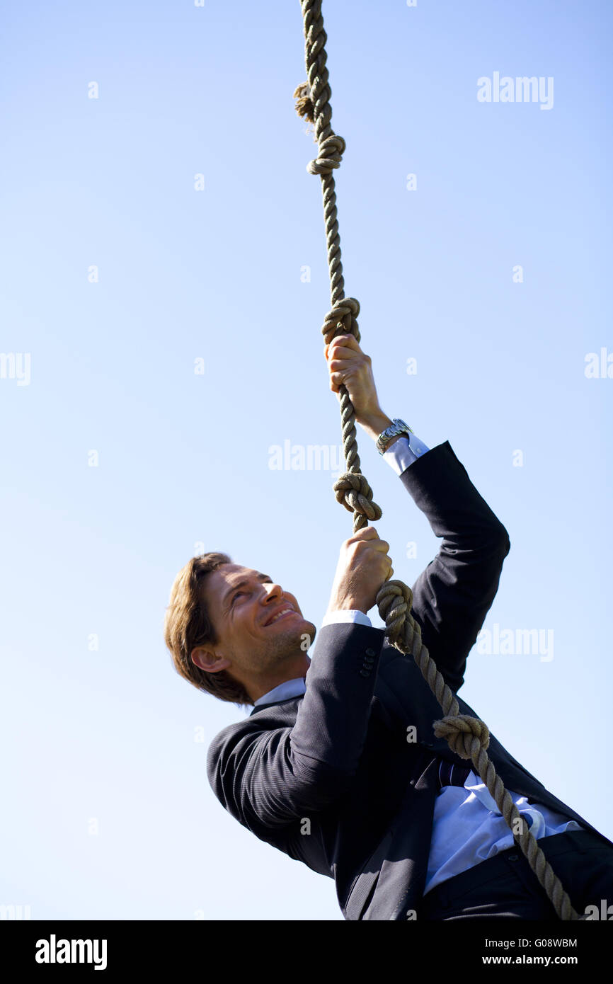 Businessman climbing rope Stock Photo - Alamy