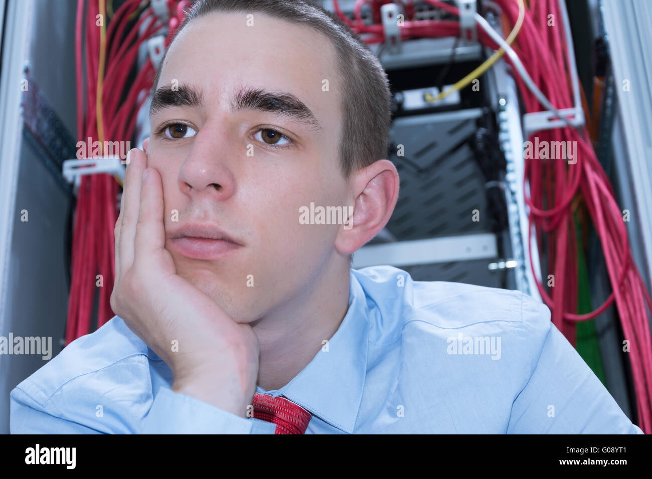 young thoughtful man sitting in front of a server Stock Photo - Alamy
