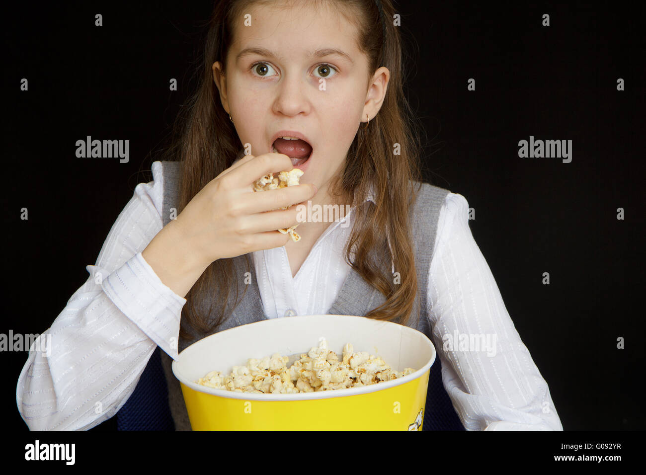 surprised girl with popcorn on a black background Stock Photo - Alamy
