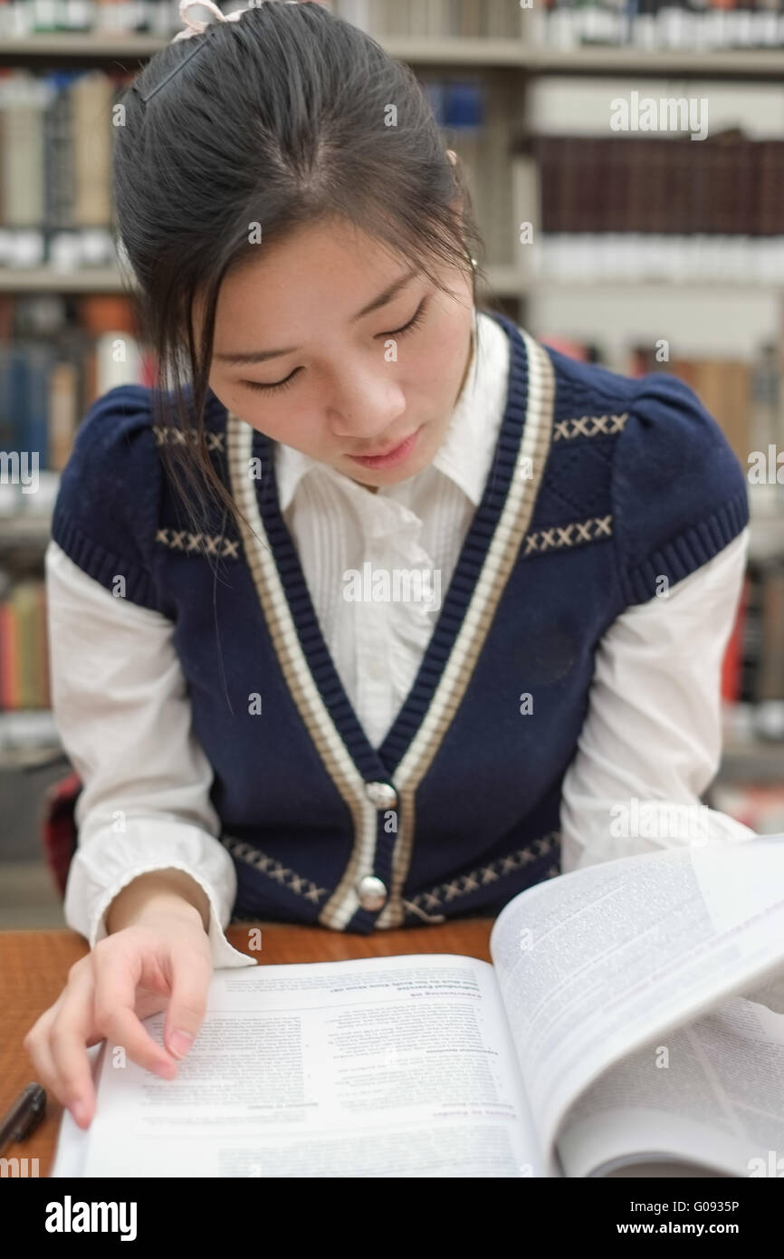 Student reading textbook near bookshelf Stock Photo - Alamy