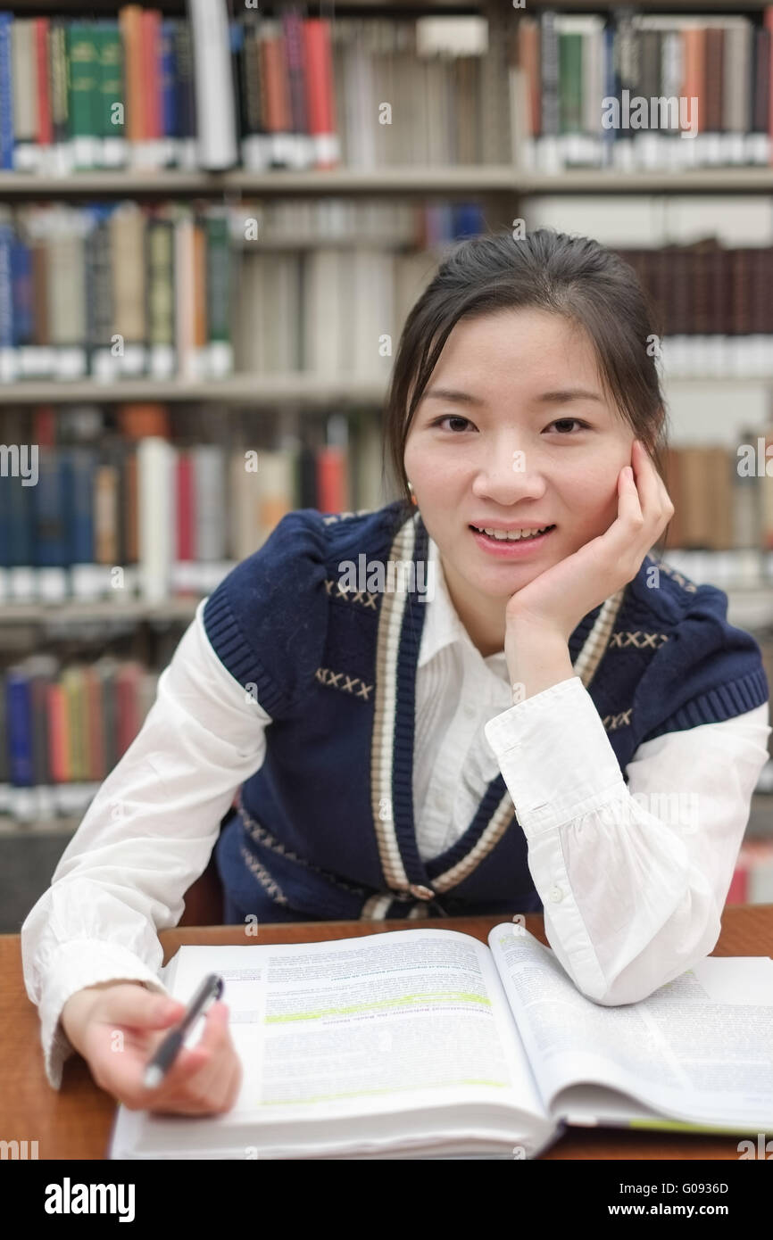 Student doing homework near bookshelf Stock Photo - Alamy