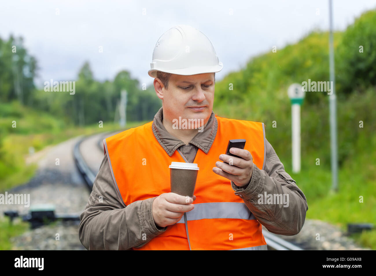 Worker with cell phone and coffee on the railway Stock Photo - Alamy