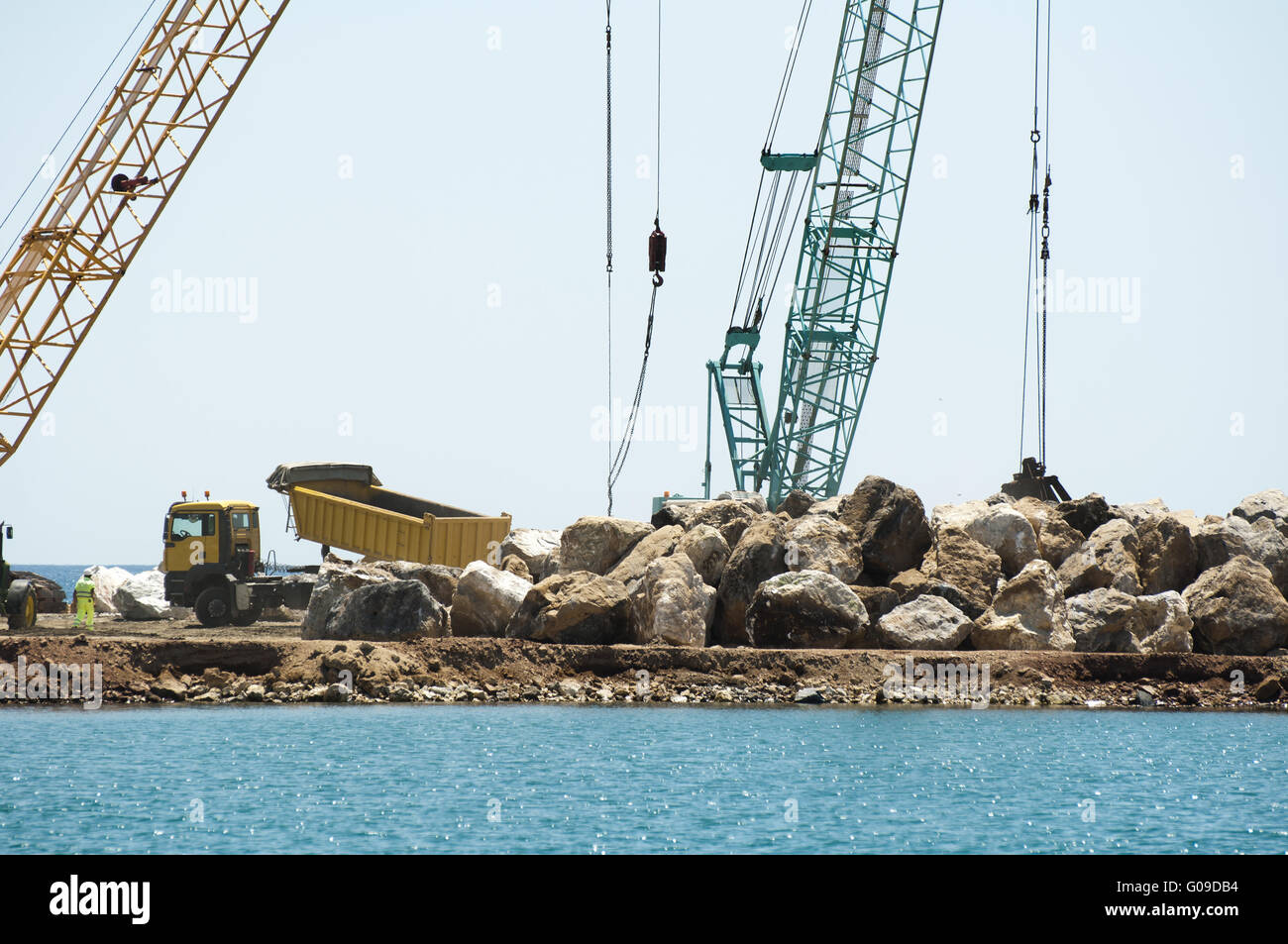 Building a dike. Cranes and excavator put stones Stock Photo - Alamy