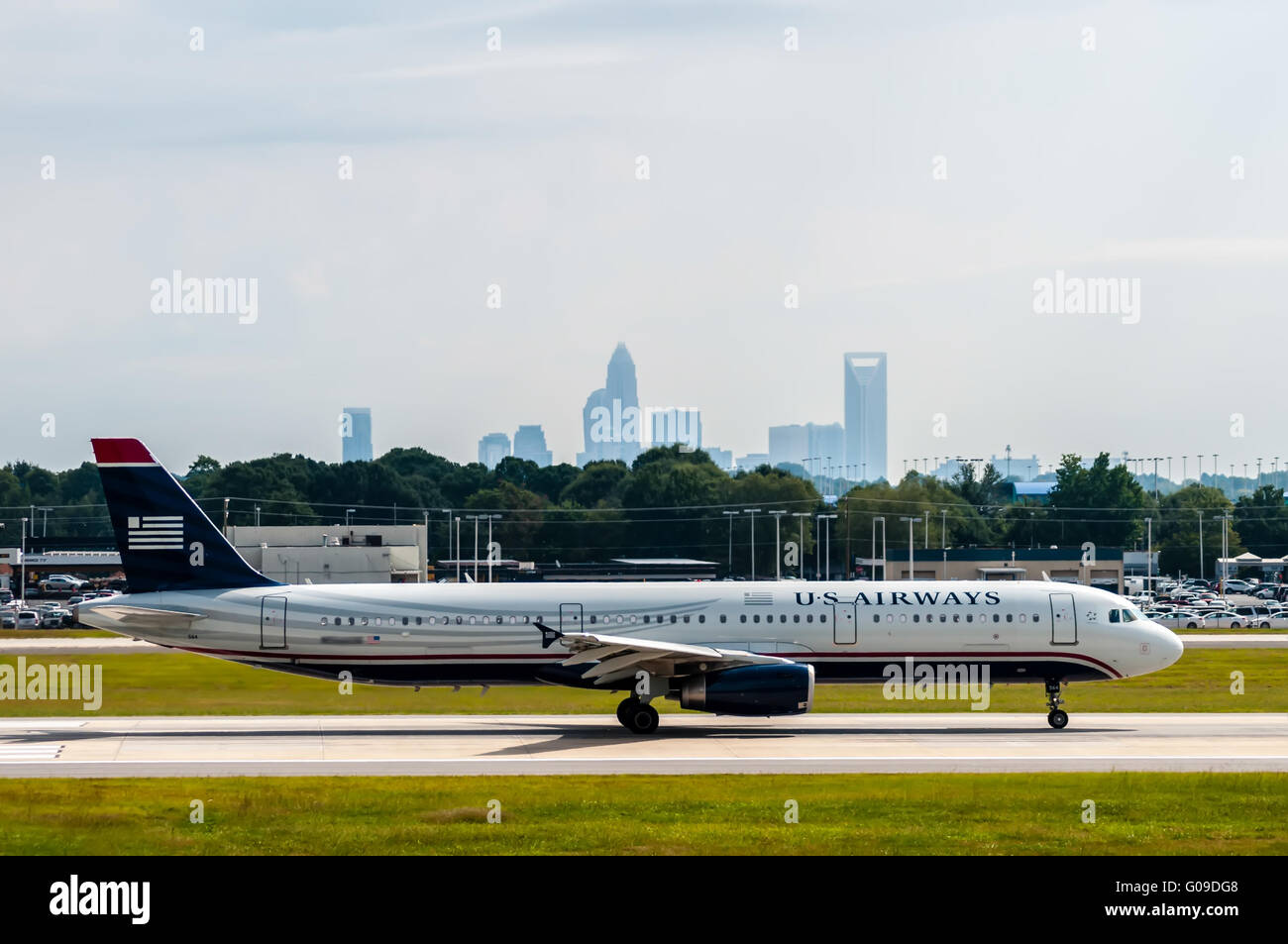 Commercial jet on an airport runway with city skyline in the background ...