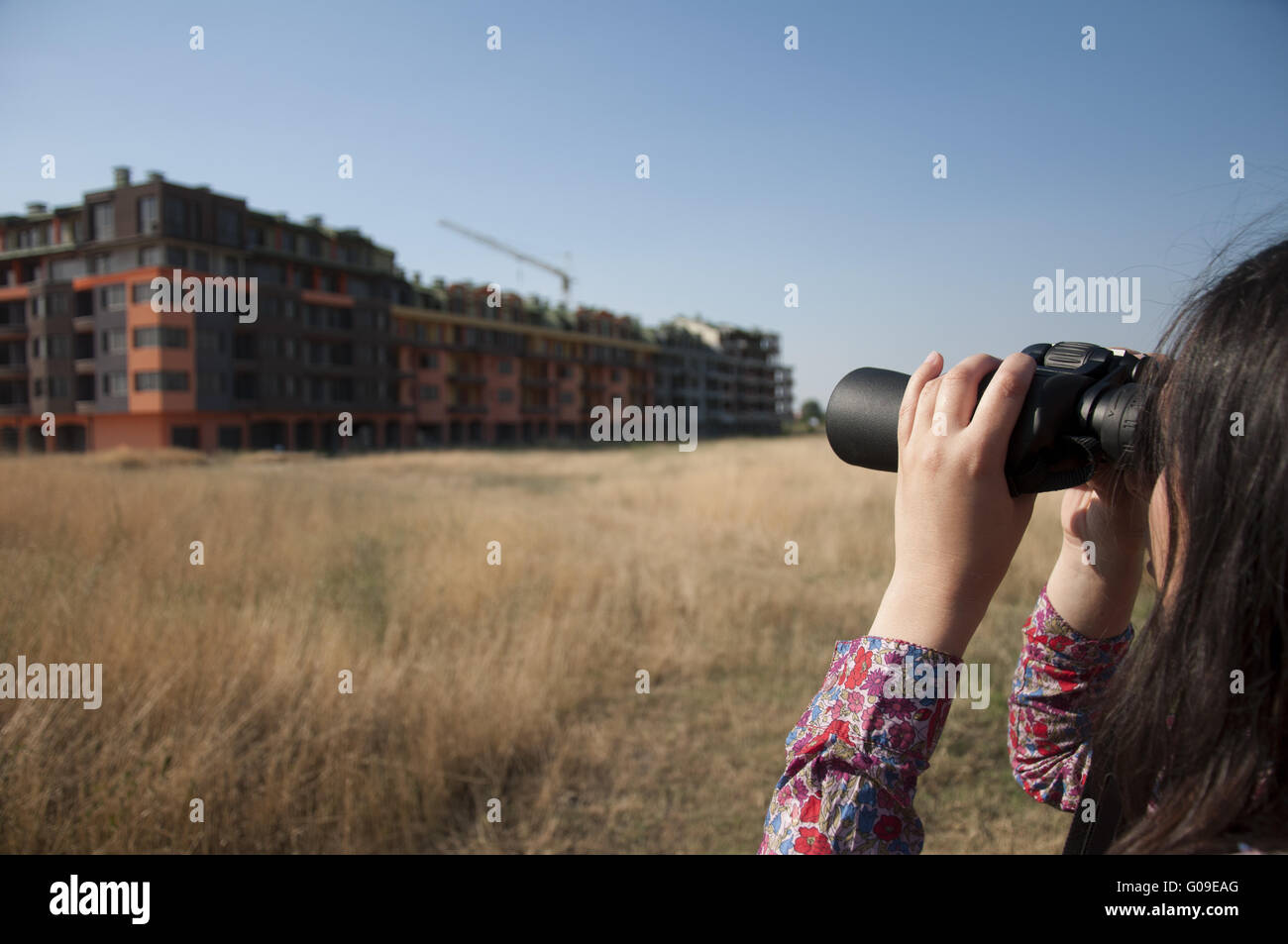 Woman watching with binoculars building construction Stock Photo - Alamy