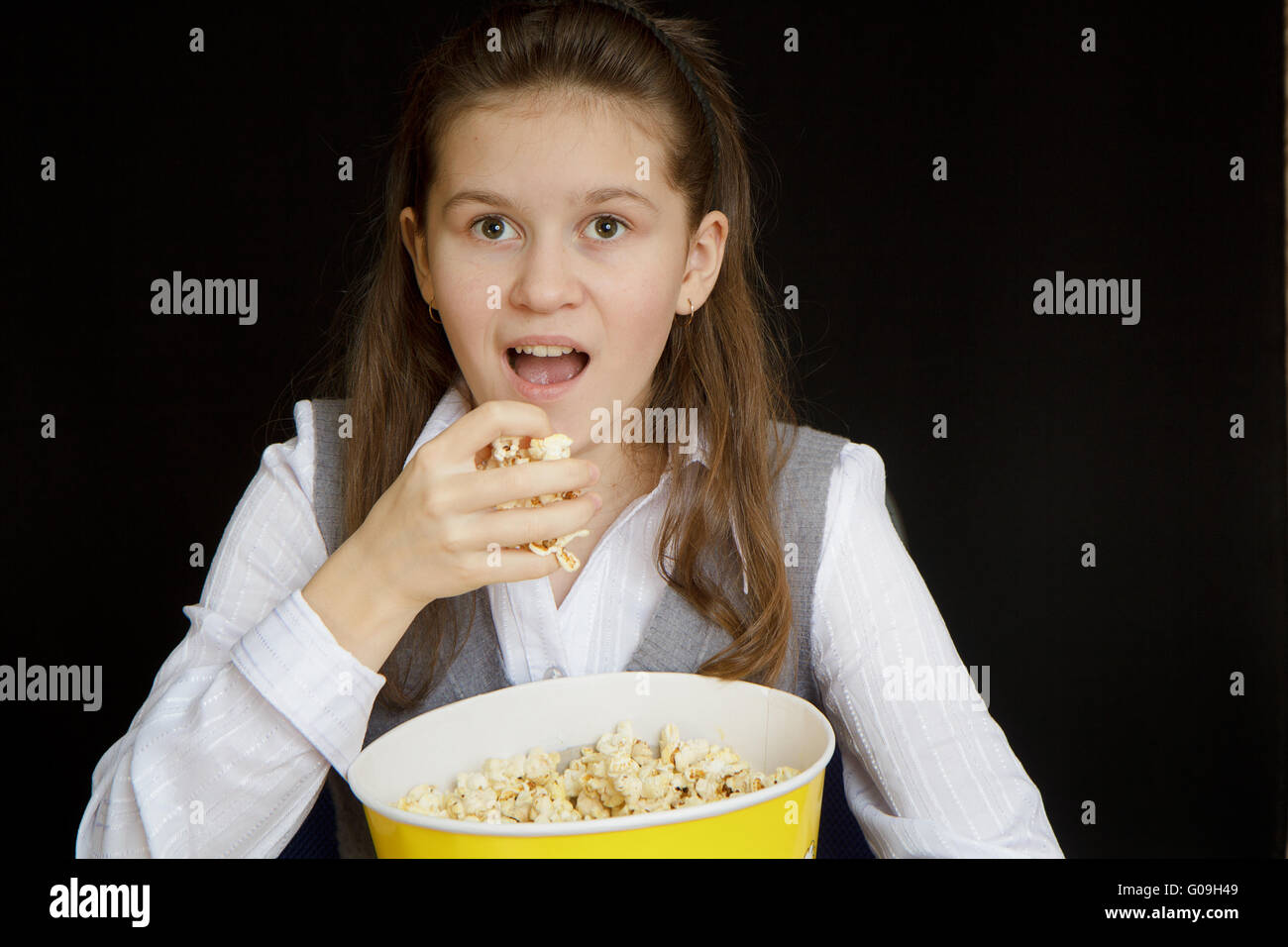 surprised girl with popcorn on a black background Stock Photo - Alamy