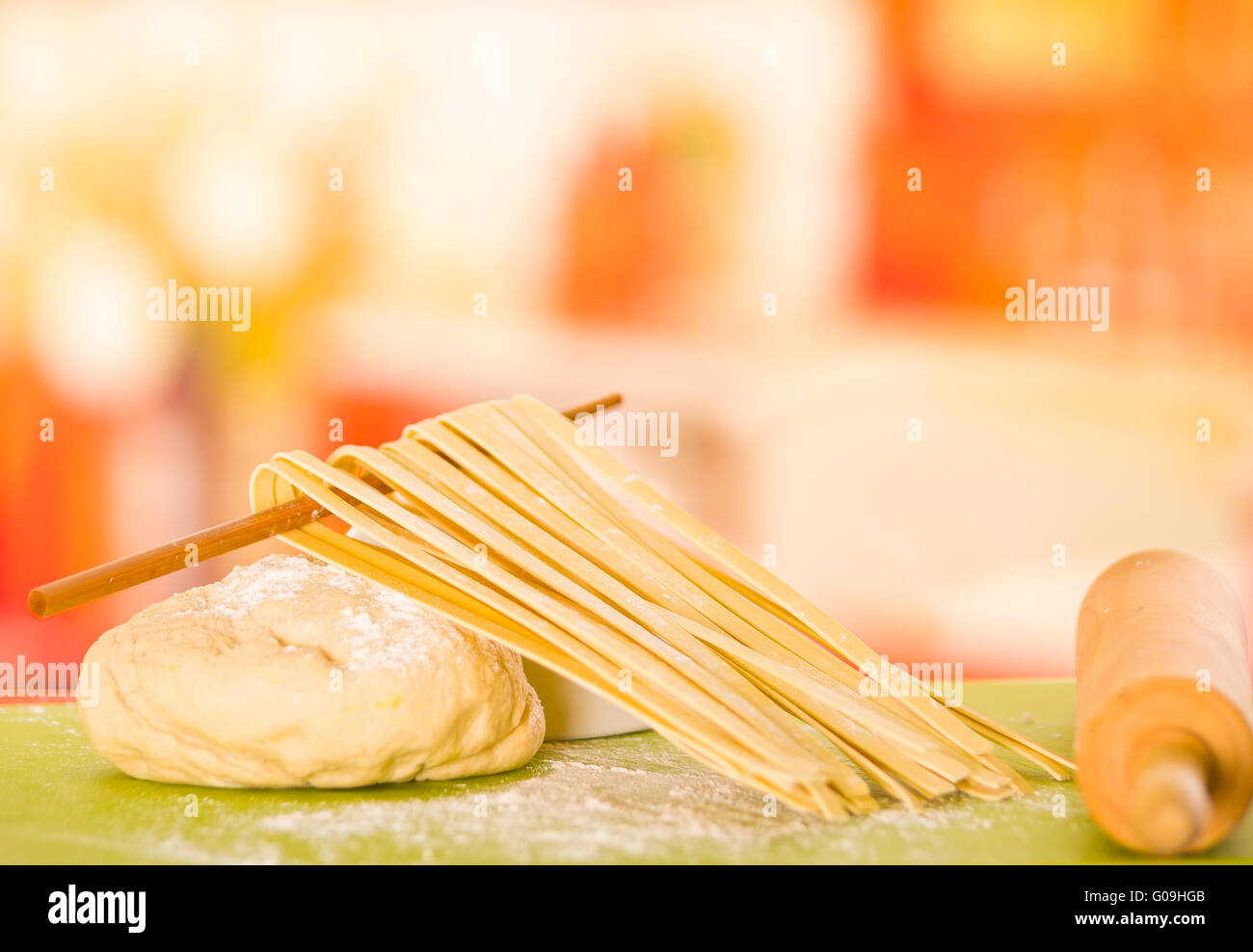 Fresh made dried spaghetti hanging across wooden stick lying on top of ...