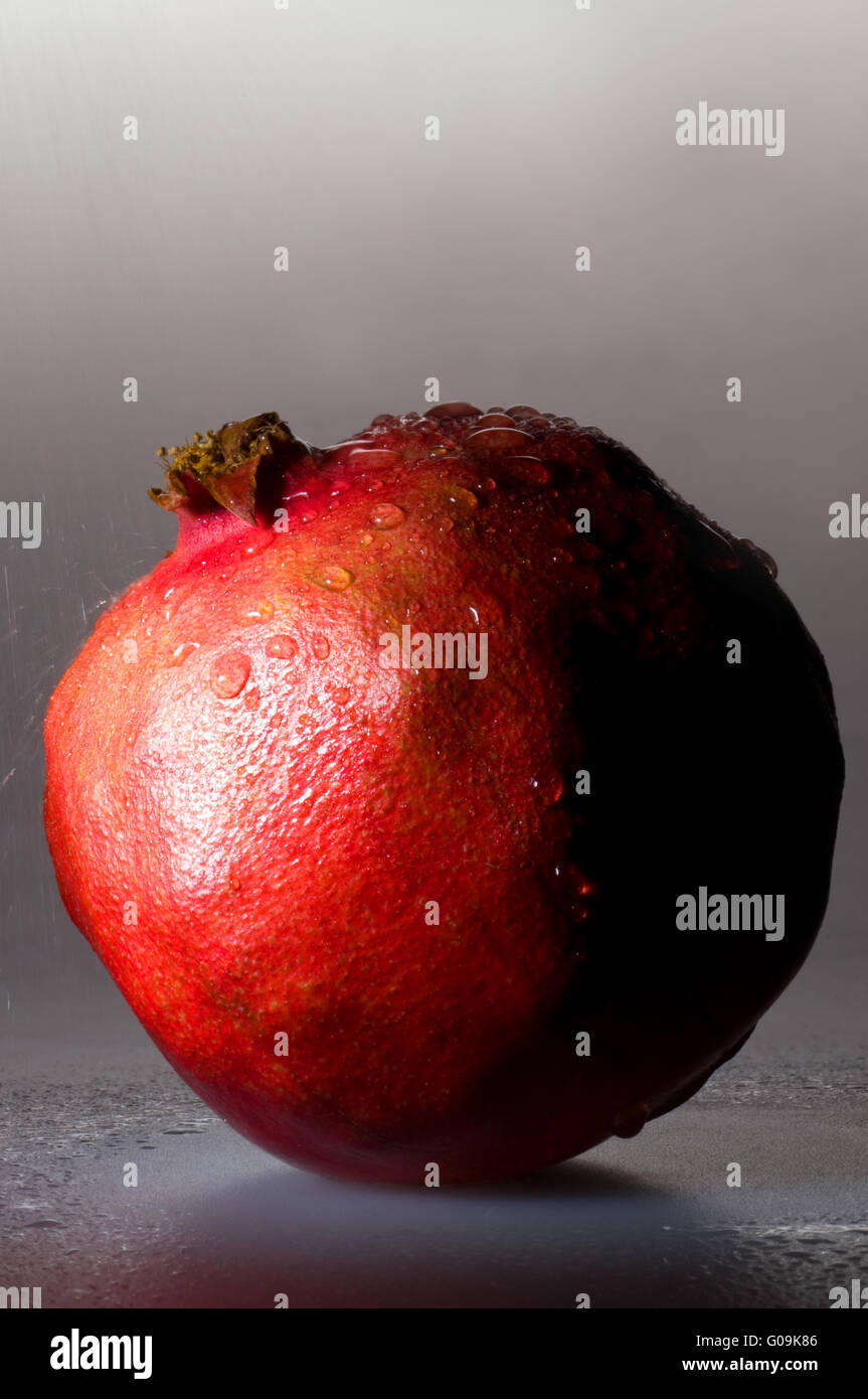 pomegranate stands on the wet gray background Stock Photo - Alamy