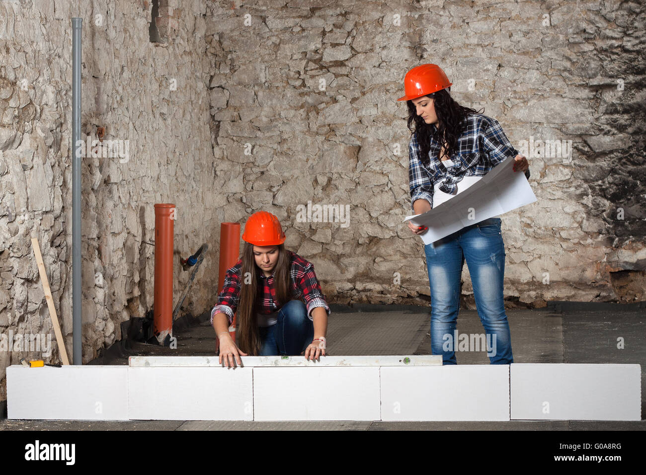 Two young long-haired woman built a new wall from blocks Stock Photo ...
