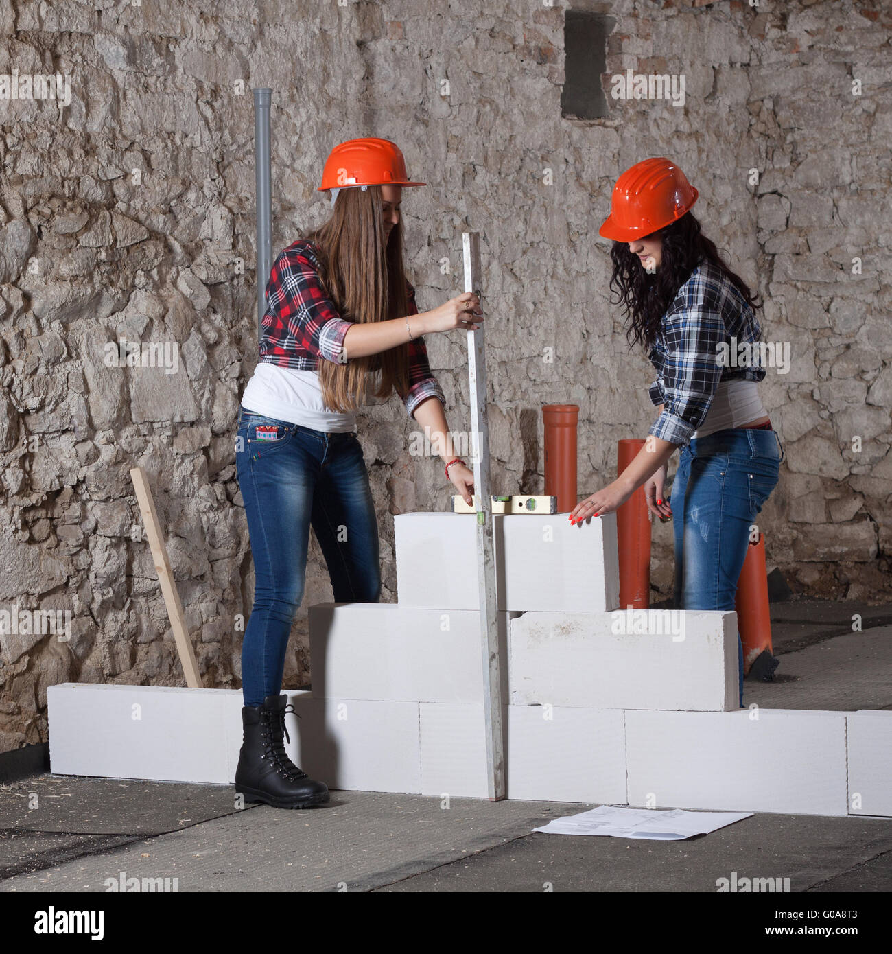 Two young long-haired woman built a new wall from blocks Stock Photo ...
