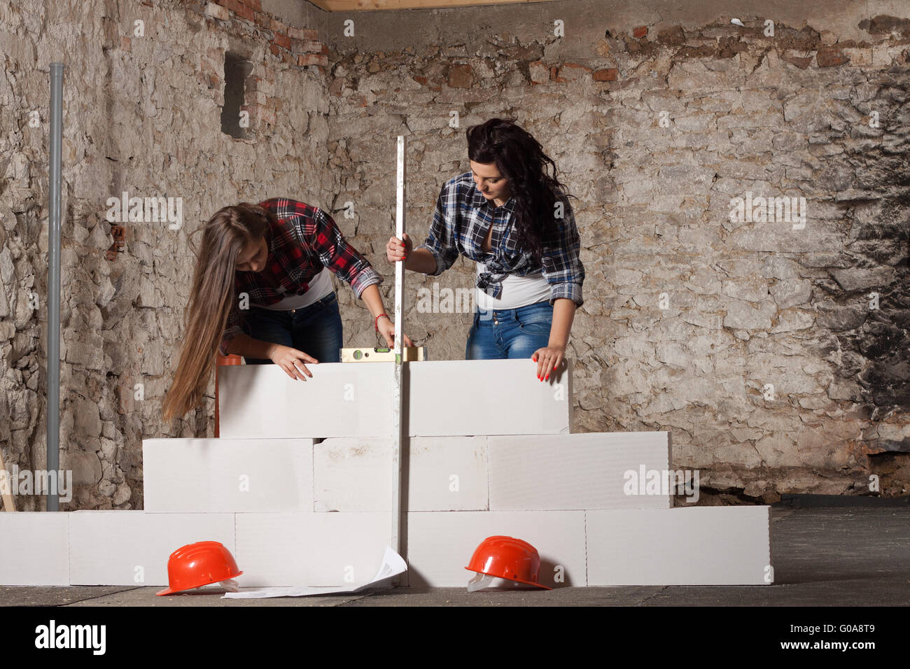 Two young long-haired woman built a new wall from blocks Stock Photo ...