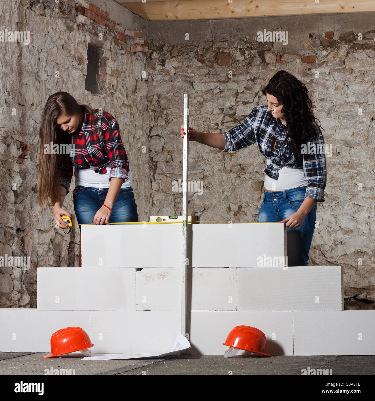 Two young long-haired woman built a new wall from blocks Stock Photo ...