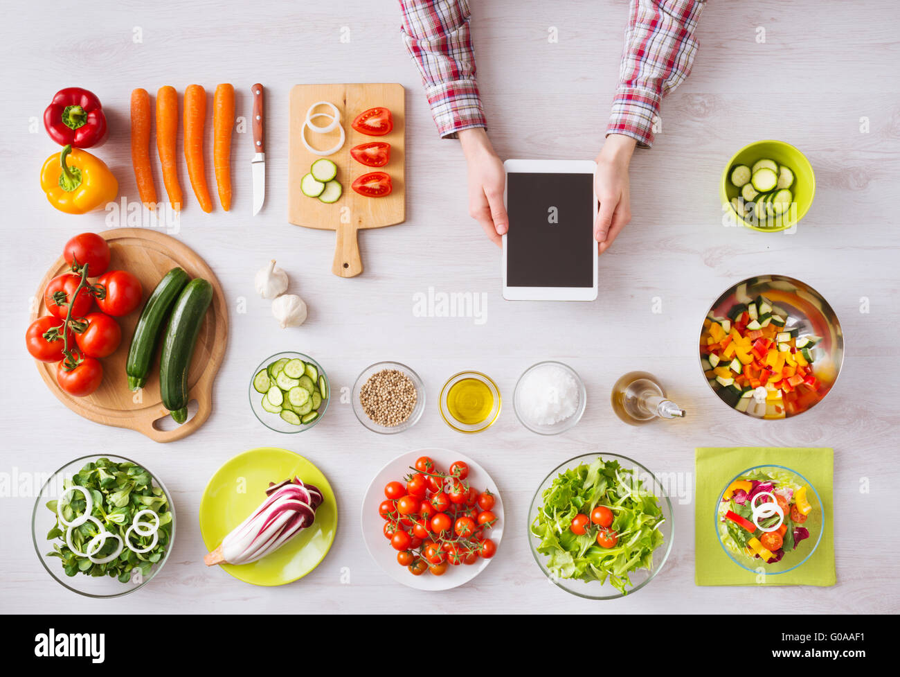 Man's hand cooking at home with touch screen tablet, fresh vegetables ...