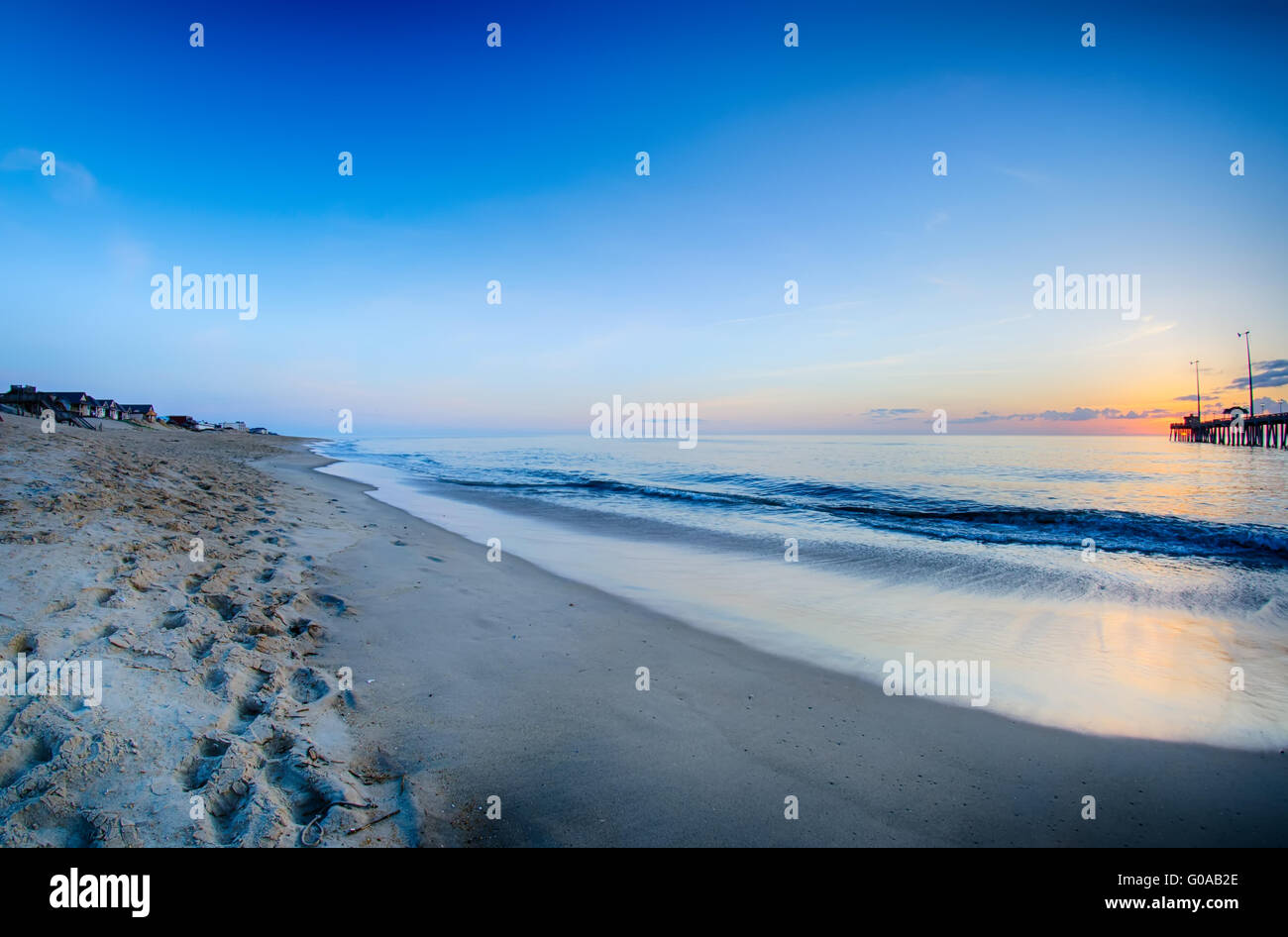 The rising sun peeks through clouds and is reflected in waves by the ...