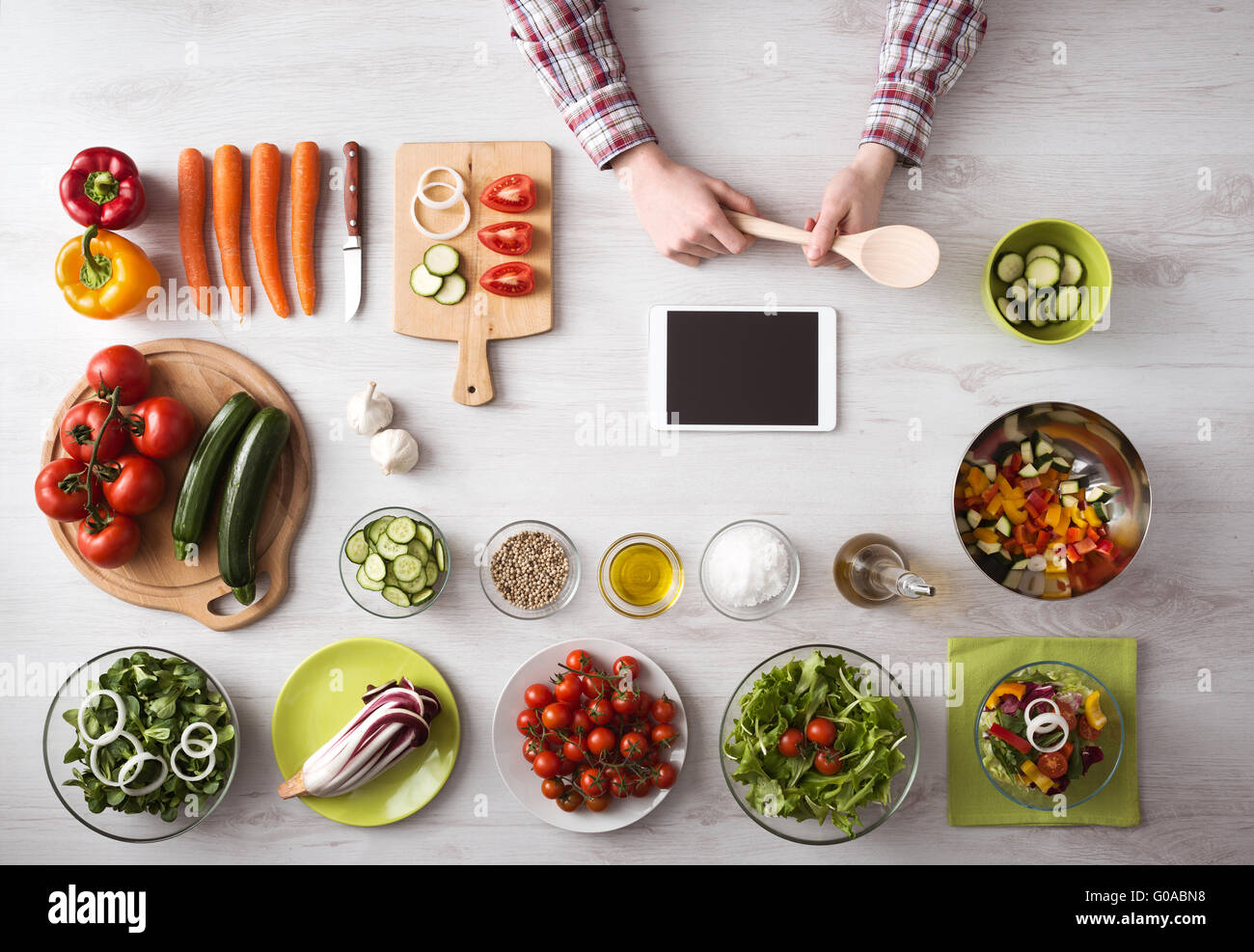 Man's hand cooking at home with touch screen tablet, fresh vegetables ...