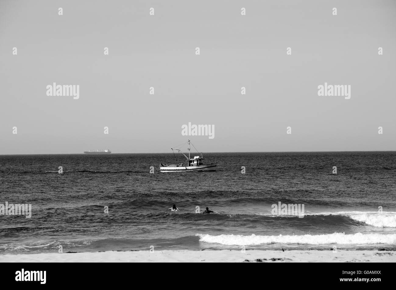 Boat catching fish and surfers catching waves Stock Photo - Alamy