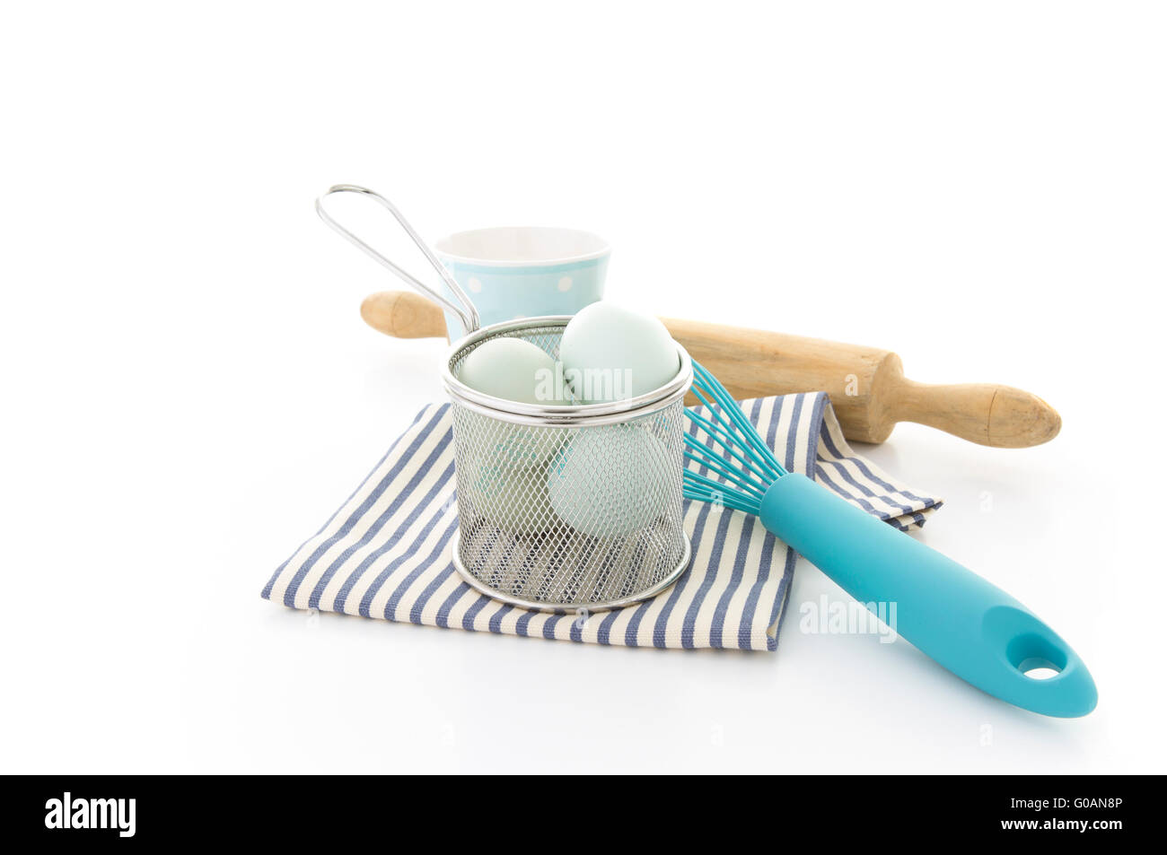 Pastry utensils with blue eggs, whisk and rolling pin on a white ...