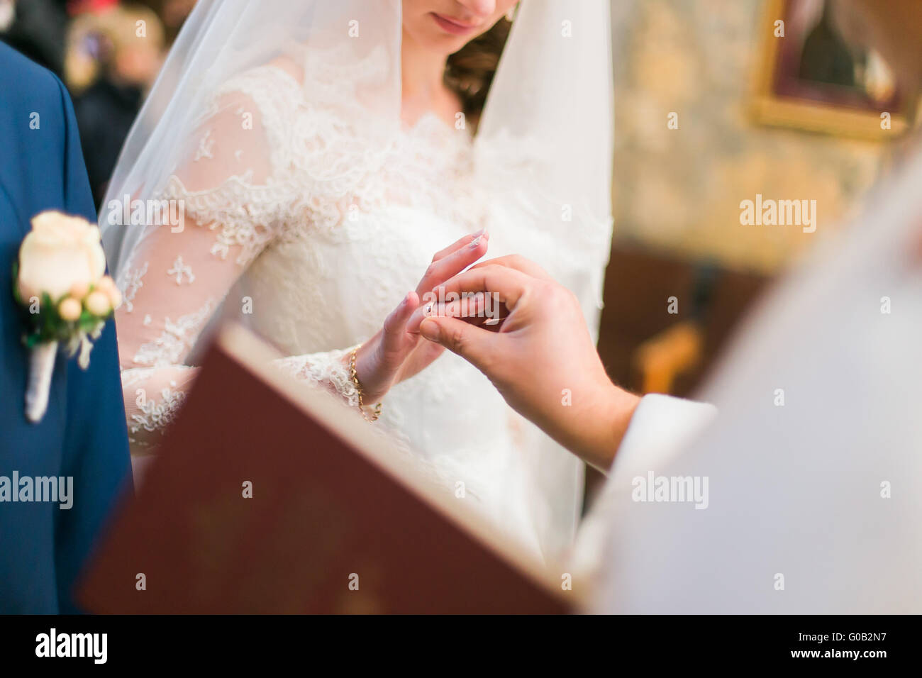 Priest is putting the ring on bride's finger during wedding ceremony ...