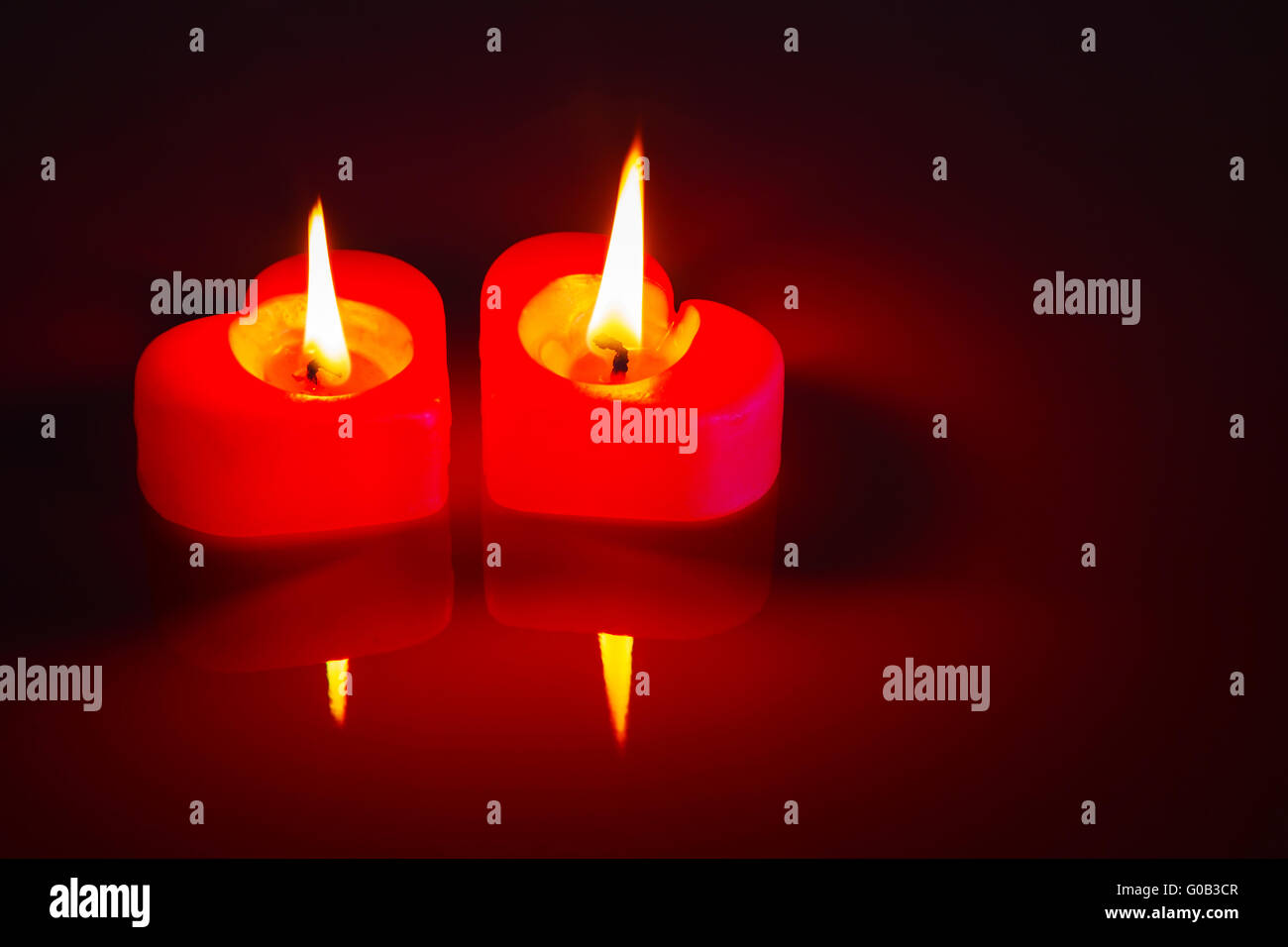 Two red burning candles against dark background Stock Photo - Alamy