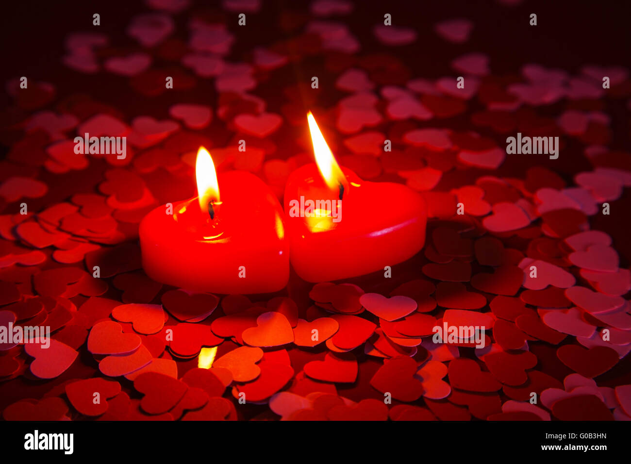 Two red burning candles against red background Stock Photo - Alamy
