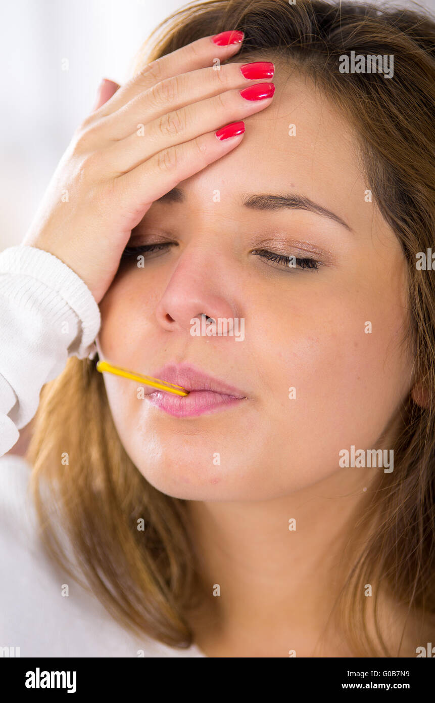 Closeup headshot brunette sick with the flu holding her head ...