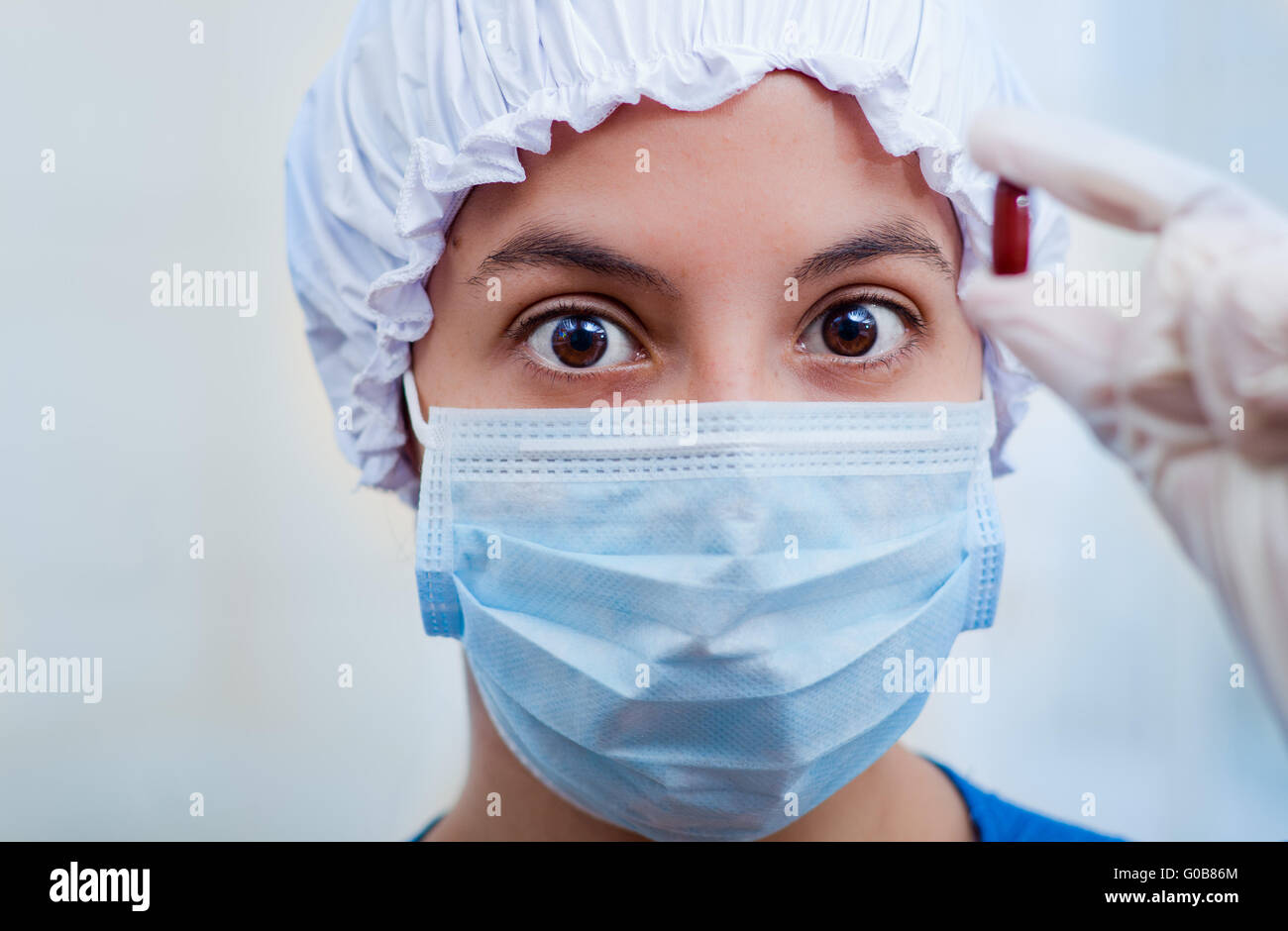 Nurse wearing bouffant cap and facial mask holding up brown pill ...